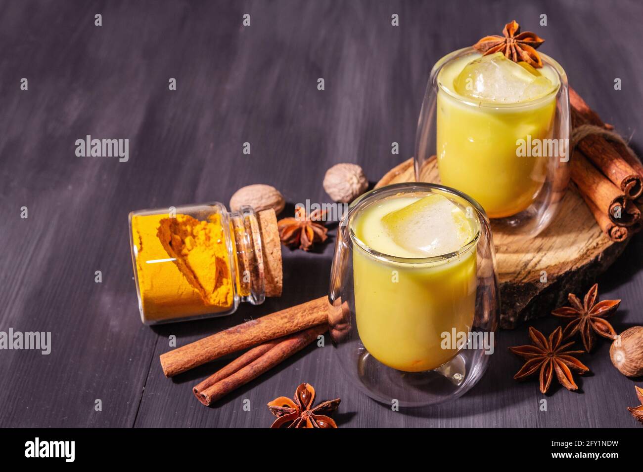 Golden turmeric milk with ice. Cinnamon, nutmeg, anise spices. Trendy ...