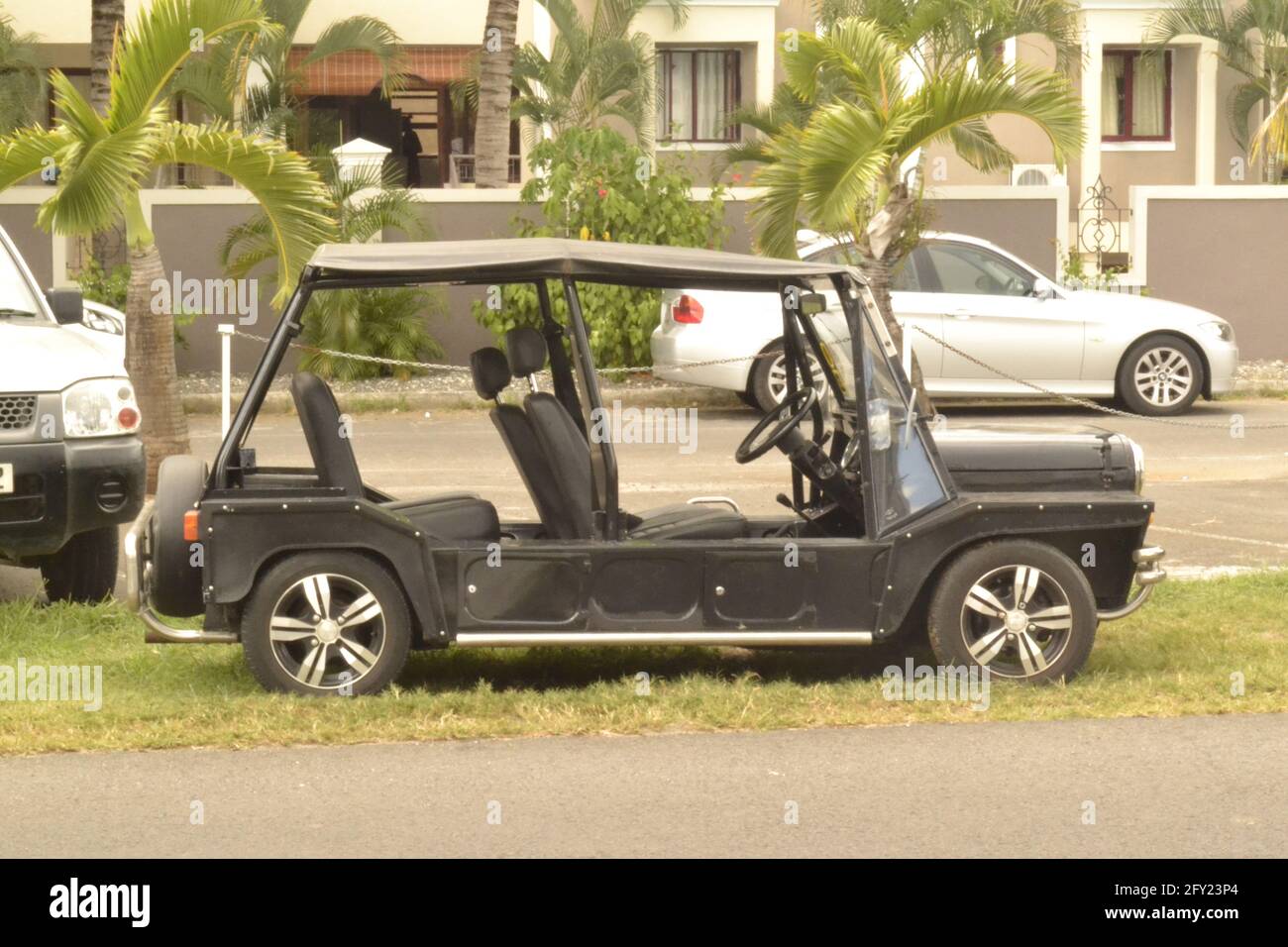 Vintage car parked on the side road along the coast of Trou aux Biches ...