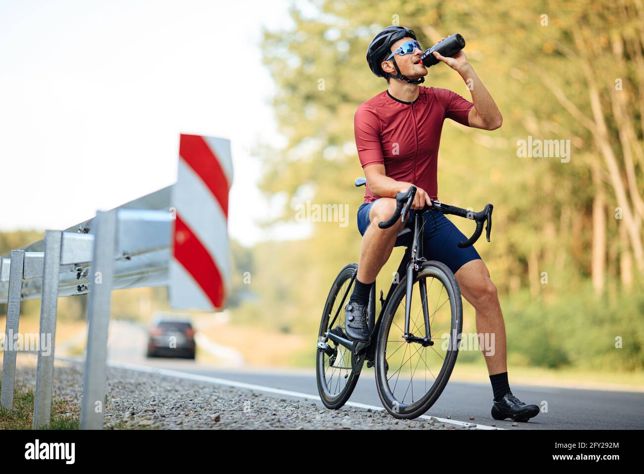 Tired road cyclist refreshing with water after ride Stock Photo - Alamy
