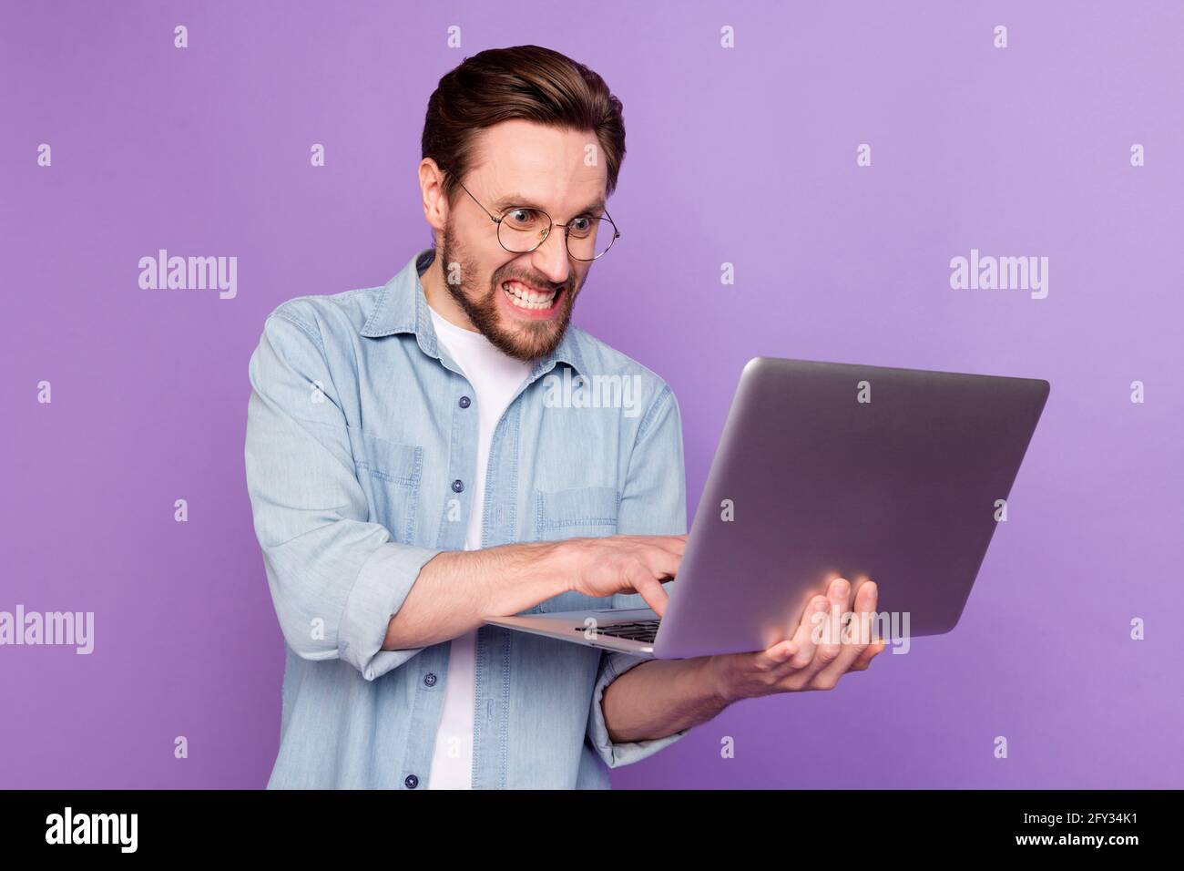 Photo of unhappy angry young man look hold laptop write letter work ...