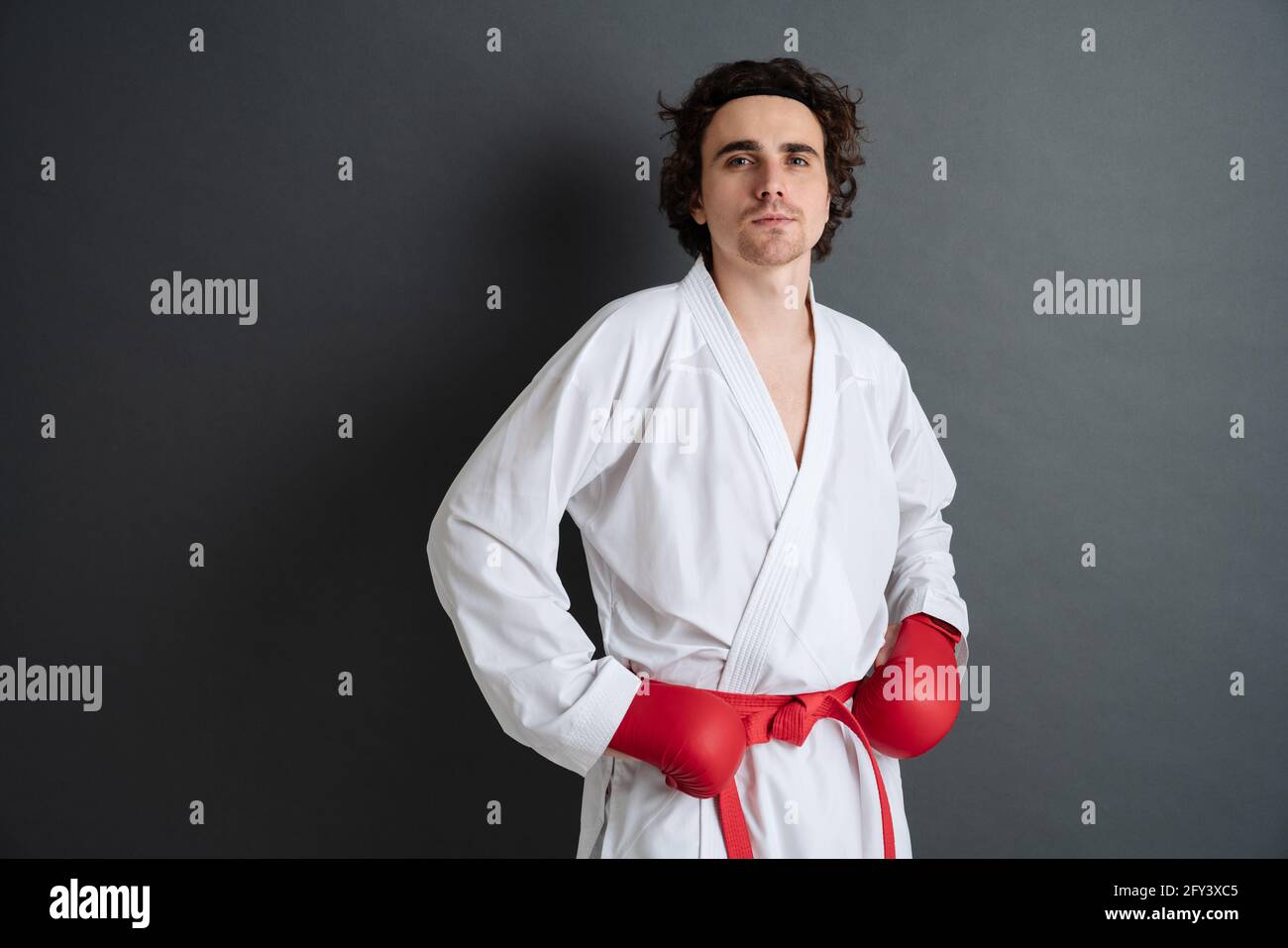 Young sportsman in kimono practicing karate with boxing gloves isolated ...