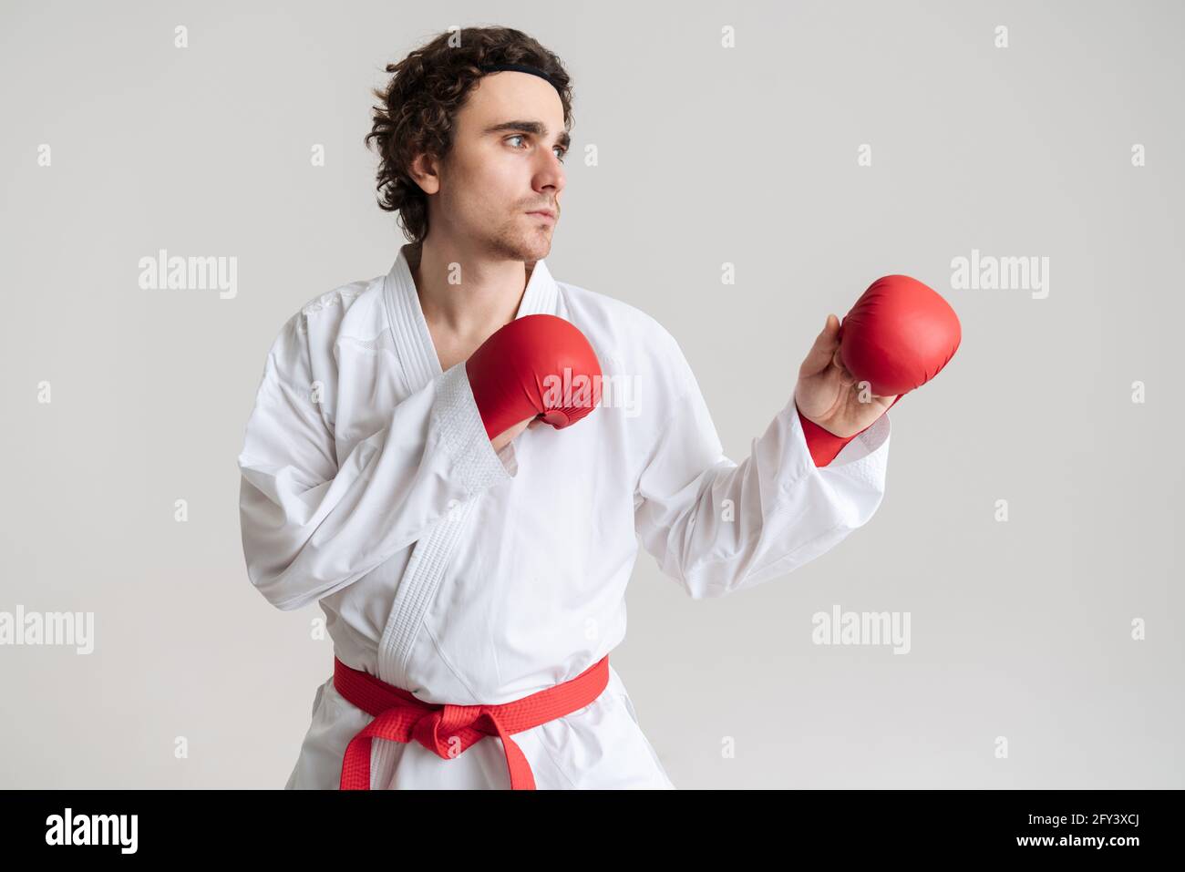 Young sportsman in kimono practicing karate with boxing gloves isolated ...