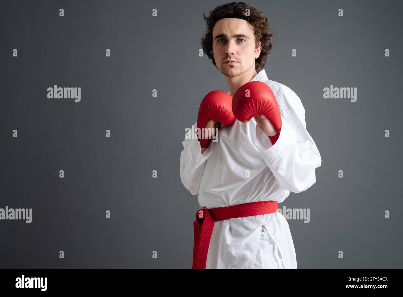 Young sportsman in kimono practicing karate with boxing gloves isolated ...