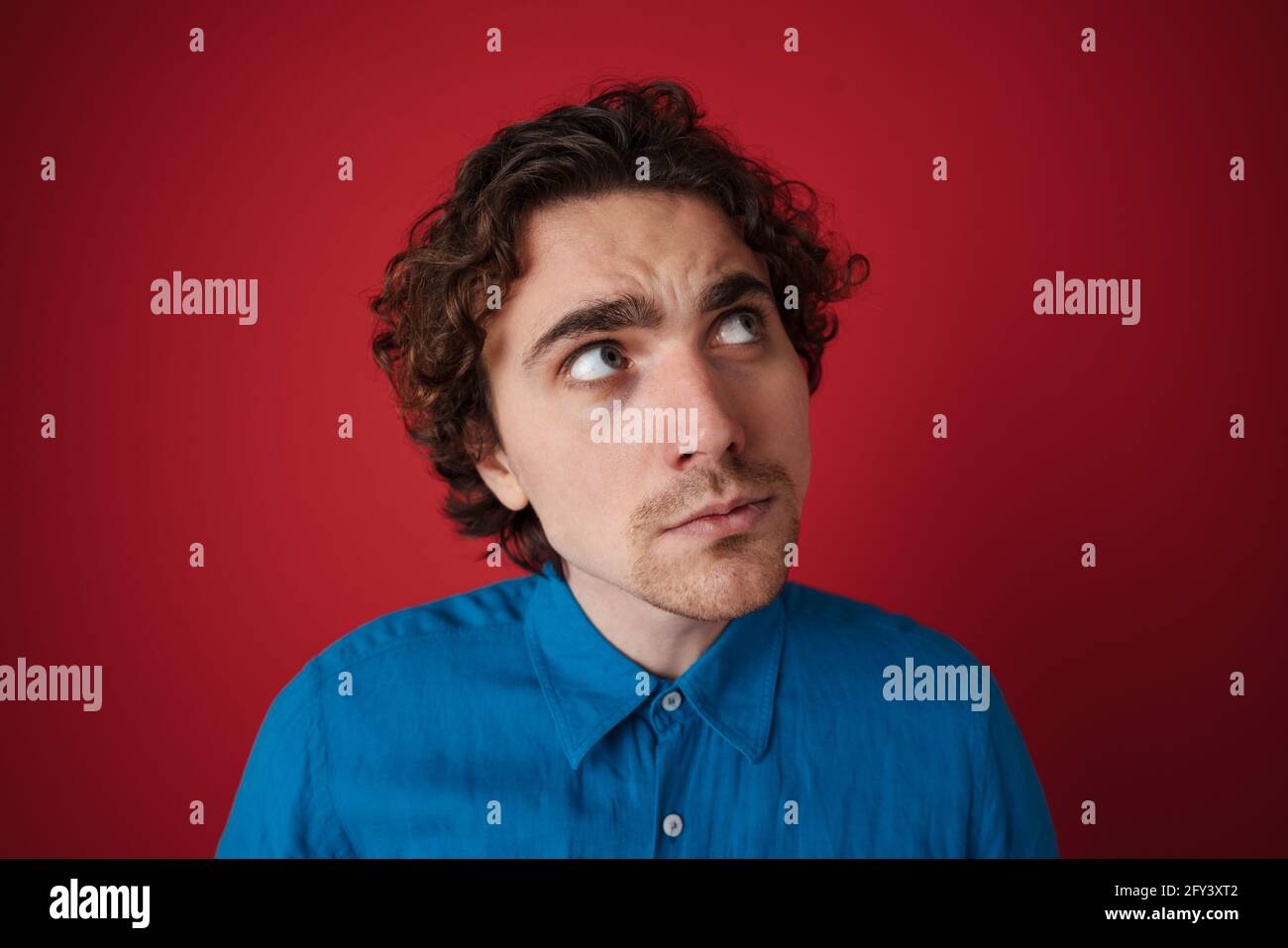 Brooding handsome man thinking and looking aside isolated over red ...
