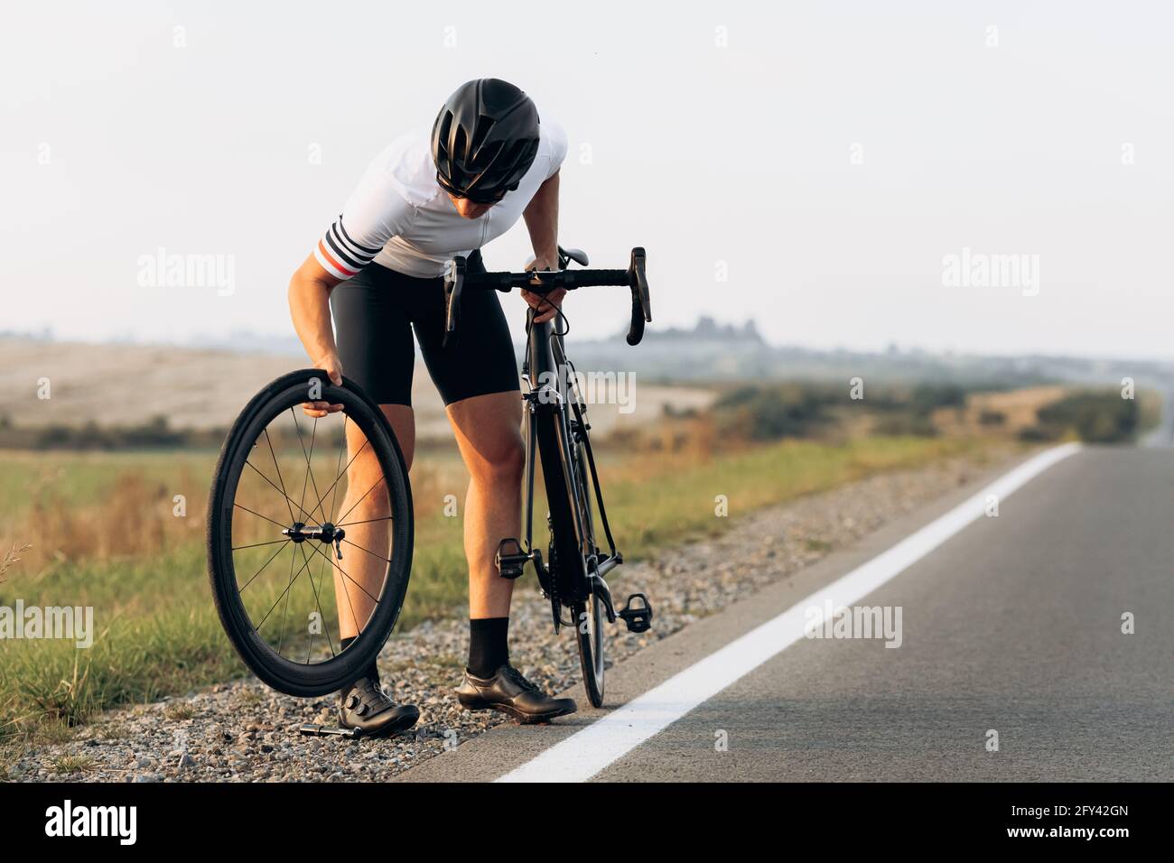 Strong cyclist in sportswear repairing wheel on bike Stock Photo - Alamy