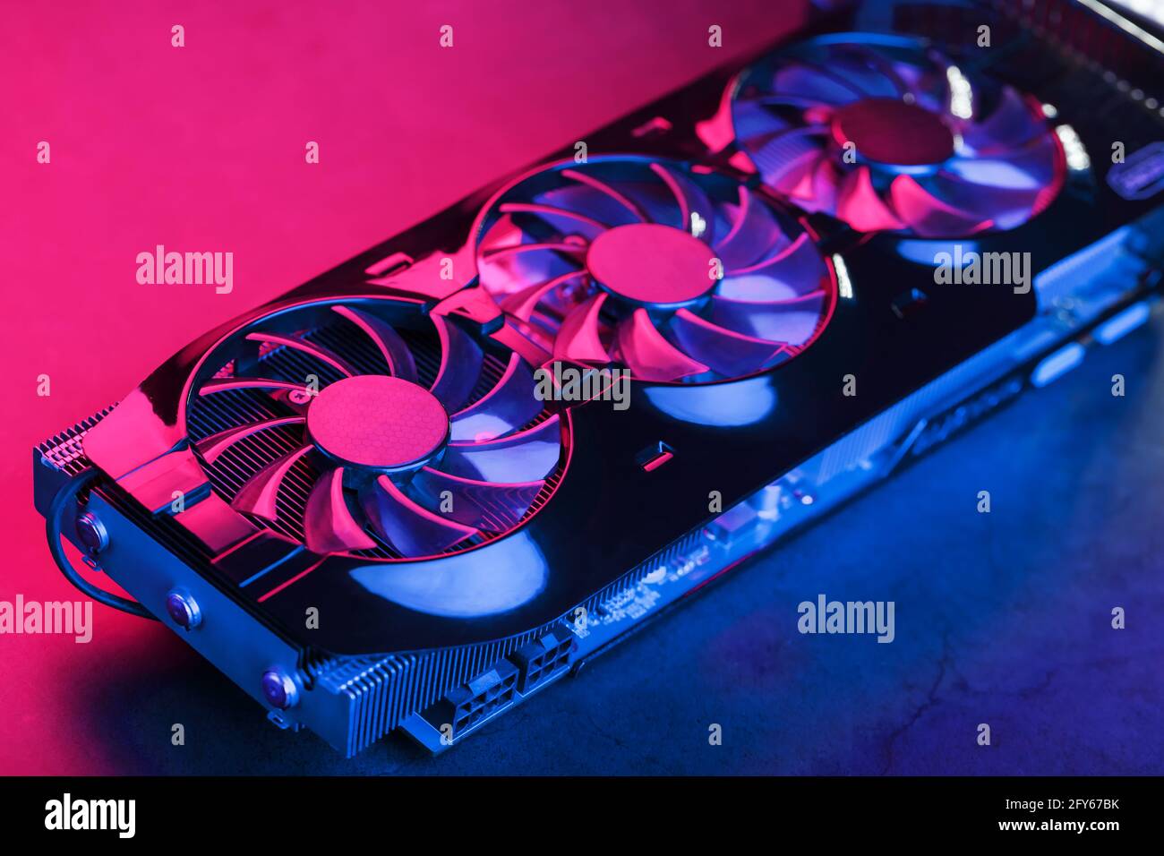 A graphics card with a row of fans with a cyanotic purple backlight in ...