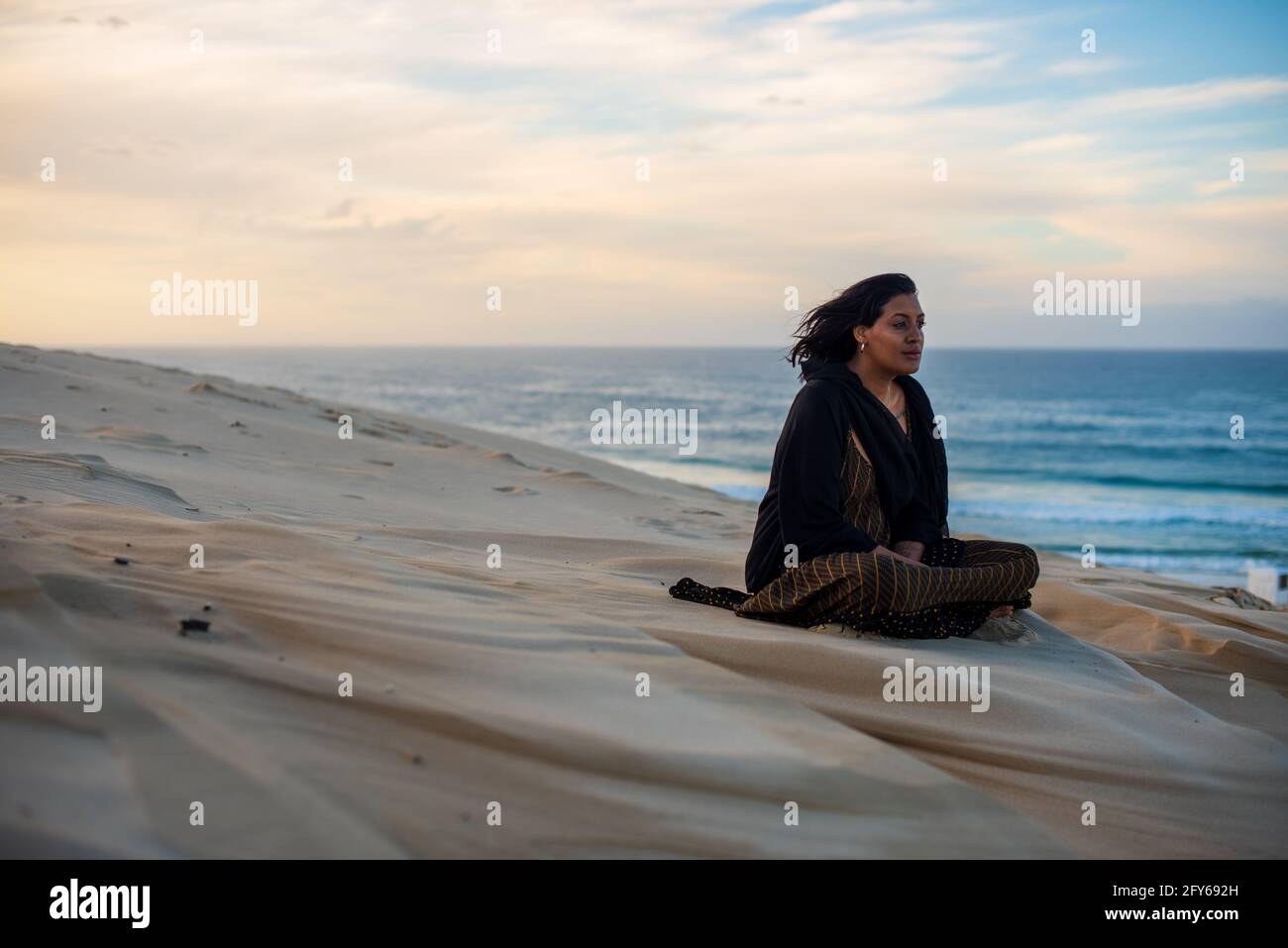 Woman sitting and contemplating at the beach Stock Photo - Alamy