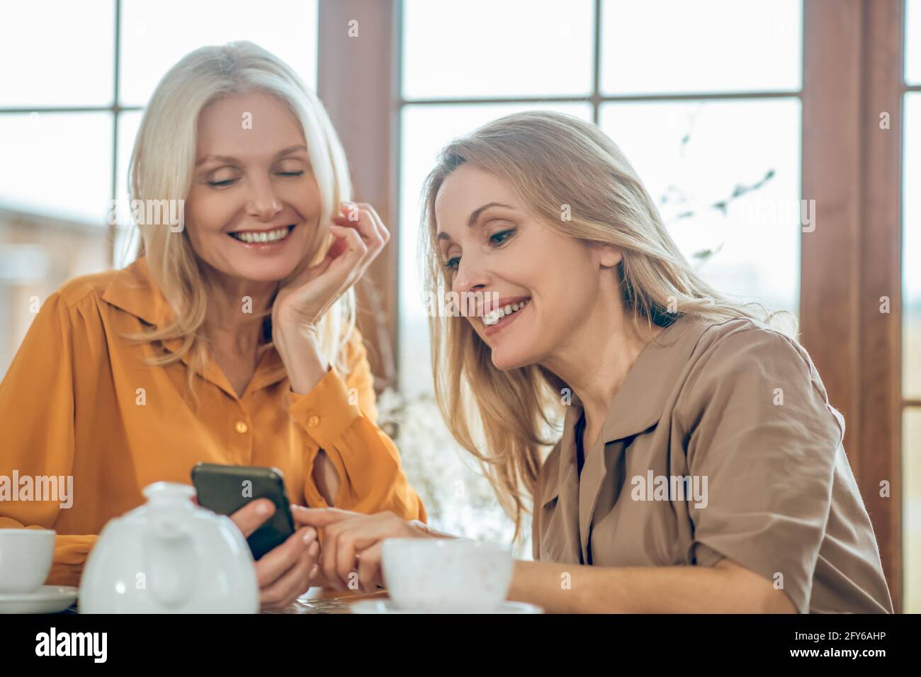 Two cute ladies spending time together and discussing photos in a ...