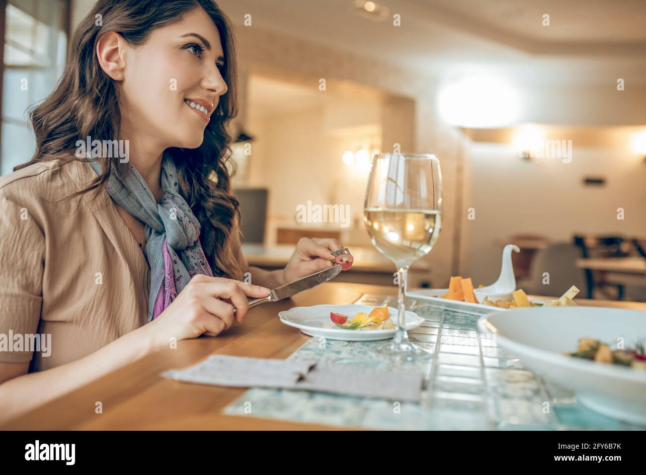 Dark-haired pretty woman sitting at the table in a restaurant and ...