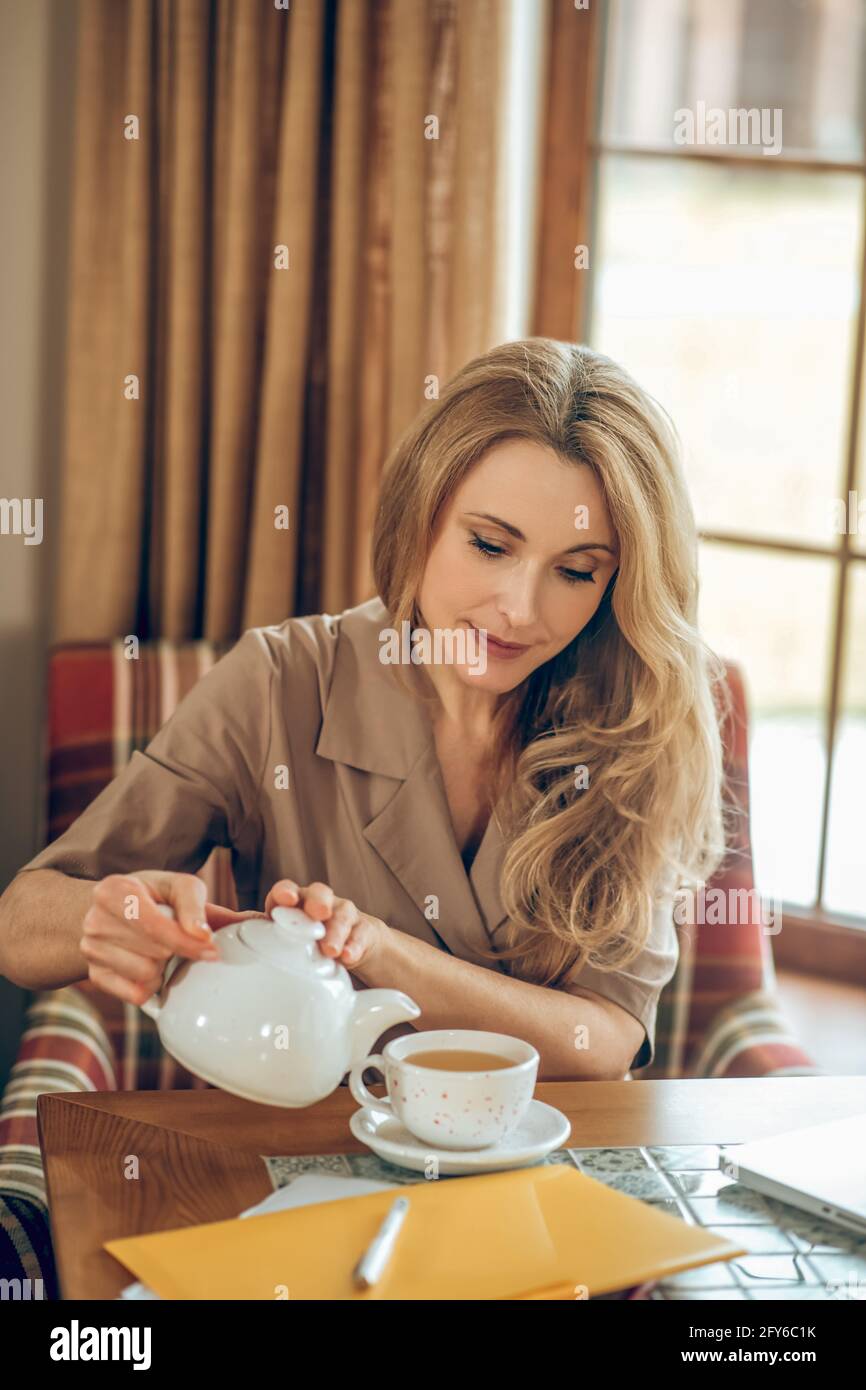 Woman pouring tea to the cup from a white tea pot Stock Photo - Alamy