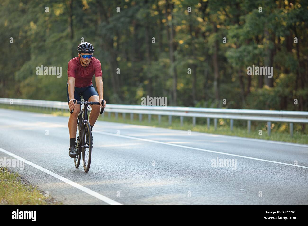 Cyclist riding bike on asphalt road among nature Stock Photo - Alamy