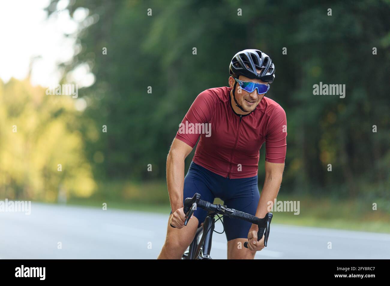 Smiling athlete in helmet and eyewear cycling on road Stock Photo - Alamy