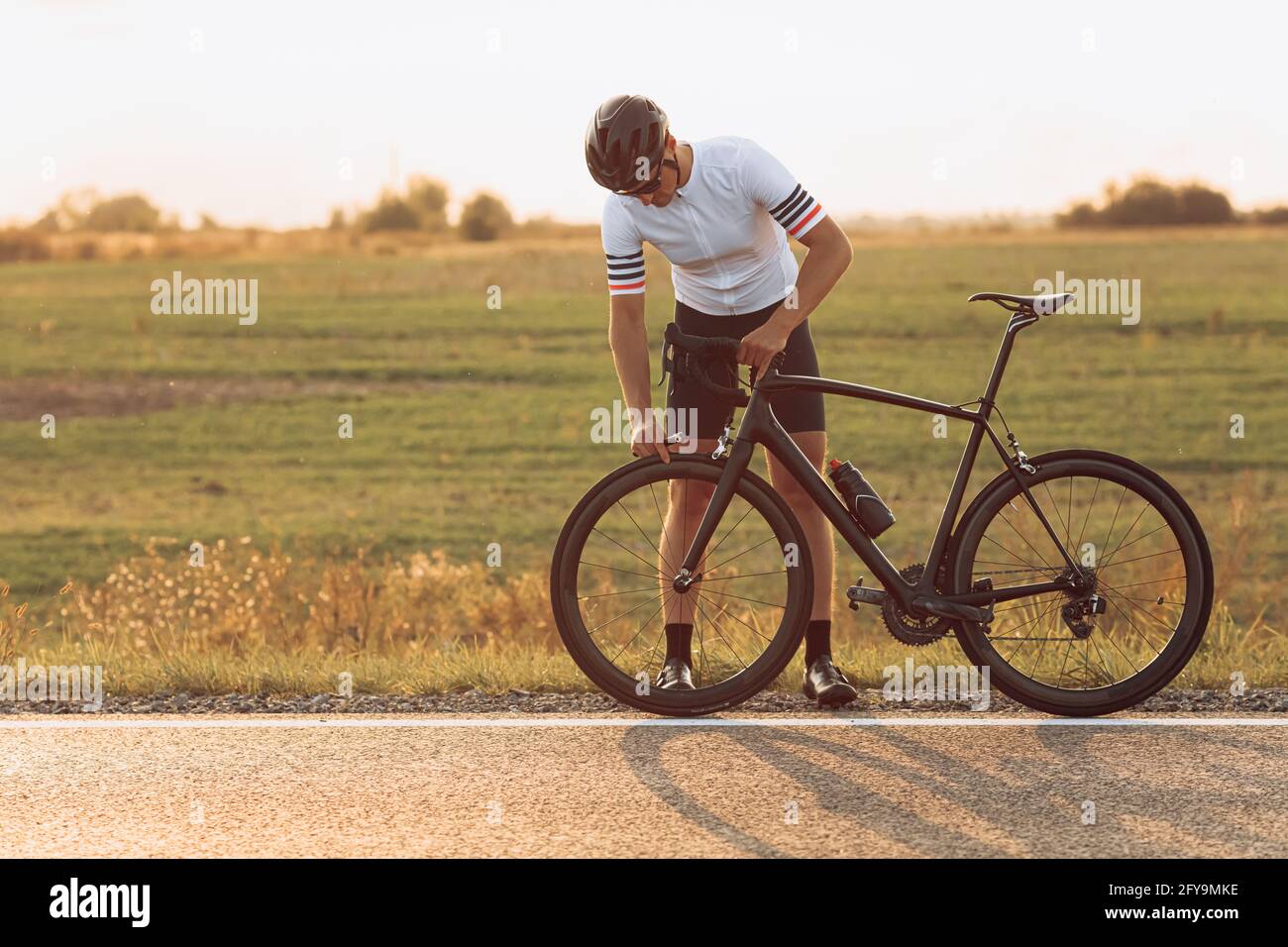 Muscular cyclist checking wheel on bike outdoors Stock Photo - Alamy
