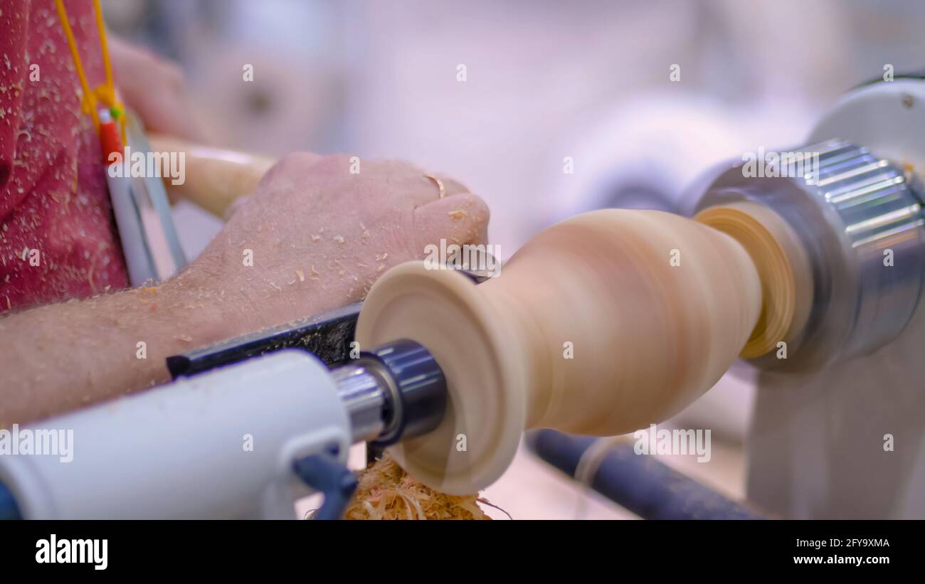 Close up: carpenter using chisel for shaping piece of wood on lathe ...