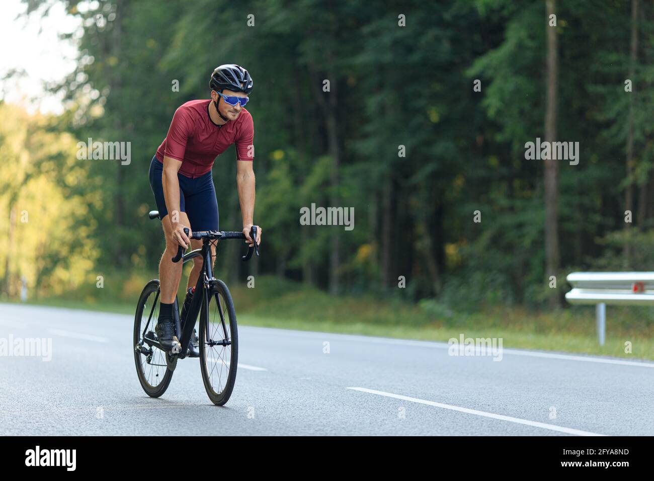 Happy cyclist in sport outfit riding bike among forest Stock Photo - Alamy