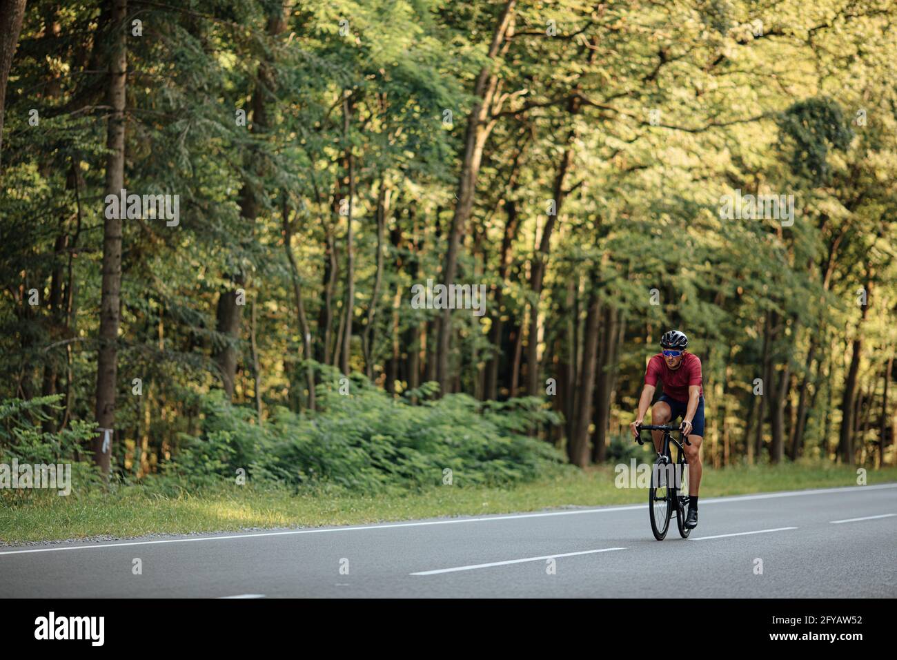 Strong guy riding bike on paved road Stock Photo - Alamy