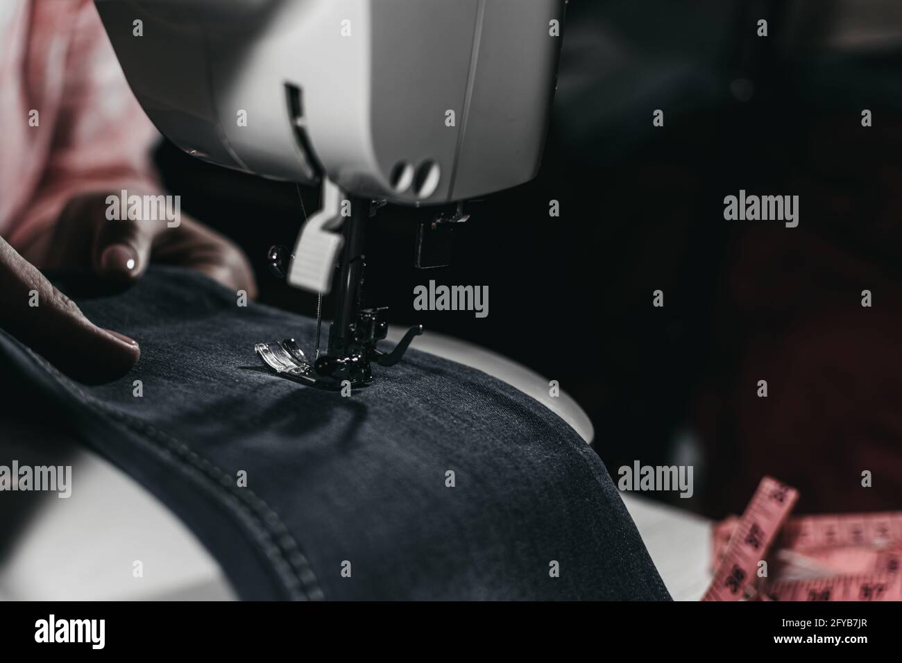 Woman sews clothes on a sewing machine in the frame visible hands ...