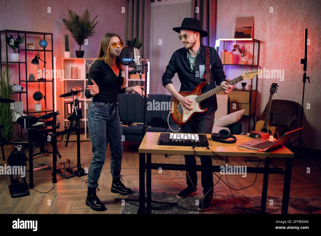 Full length portrait of stylish man and woman standing at modern studio ...