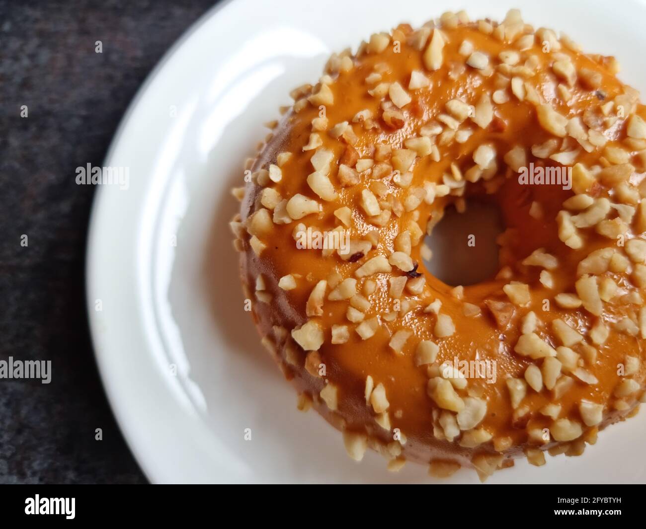 Delicious pastries. Donut covered with caramel and nuts on a white ...