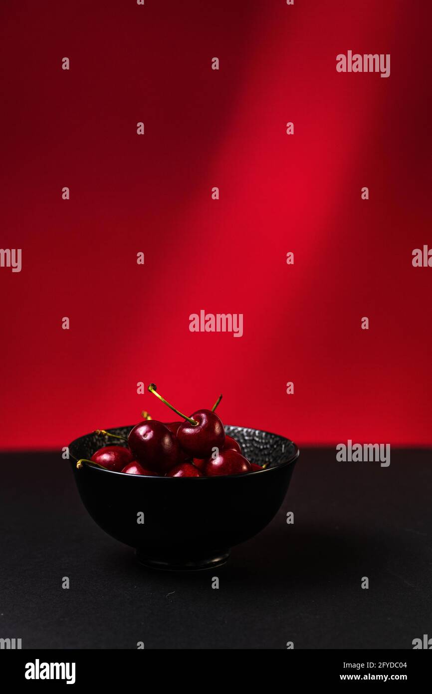 fresh red juicy cherries in a little black bowl Stock Photo - Alamy