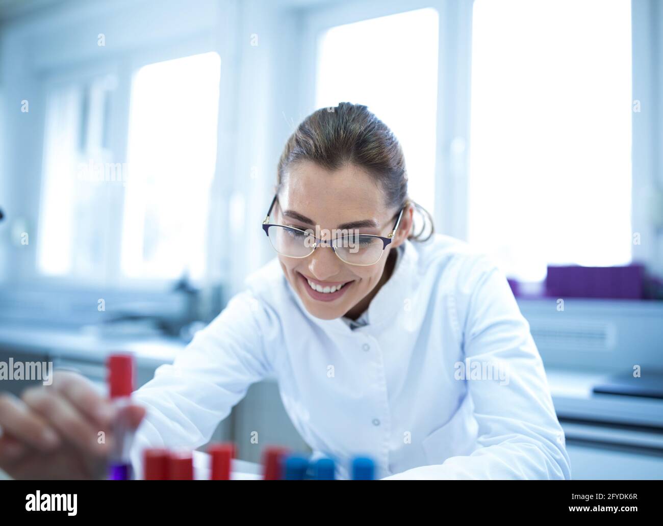 Young scientist lab technician working holding vial smiling. Satisfied ...