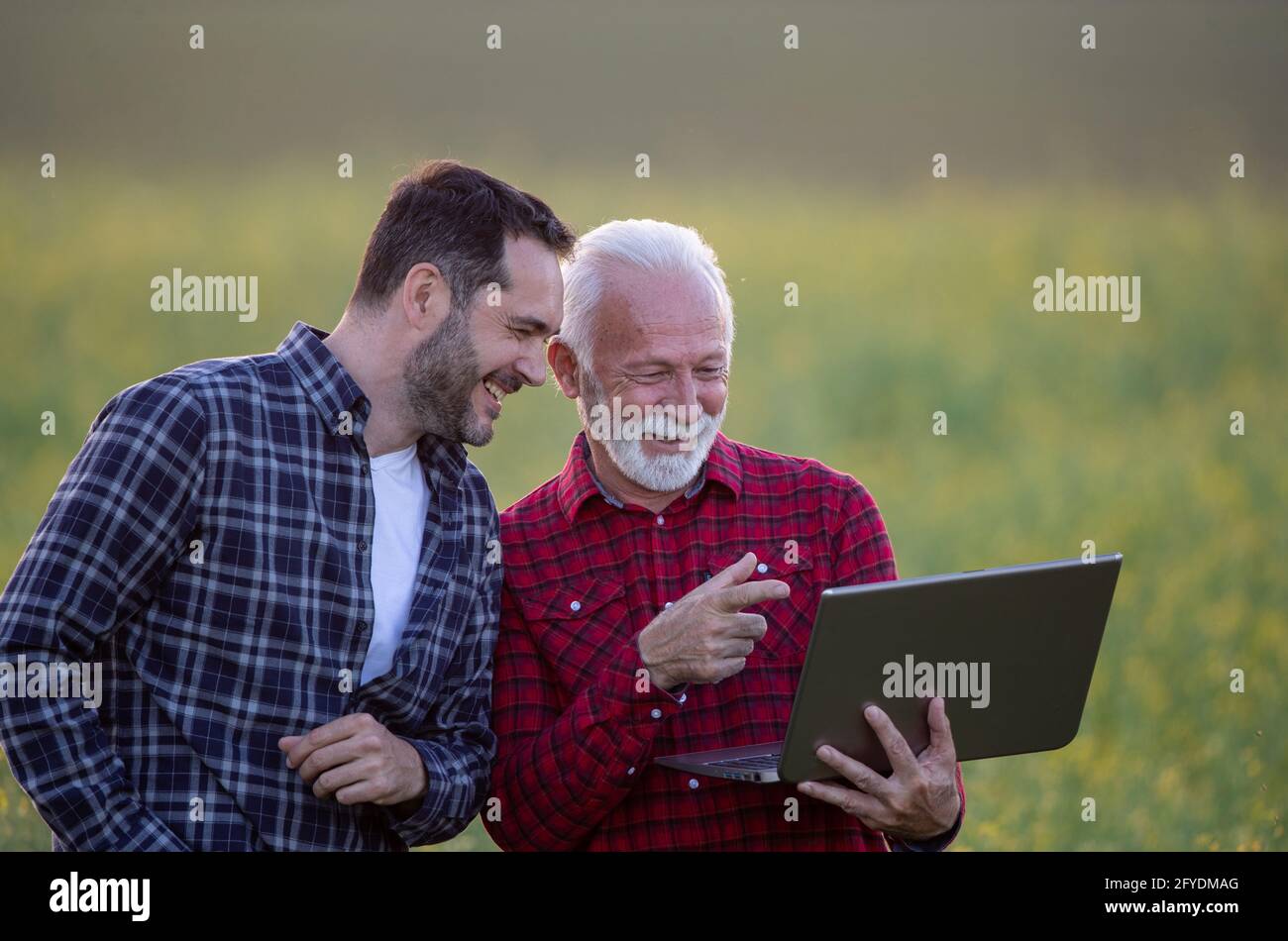 Farmers using laptop outside for agriculture.. Two men standing in ...