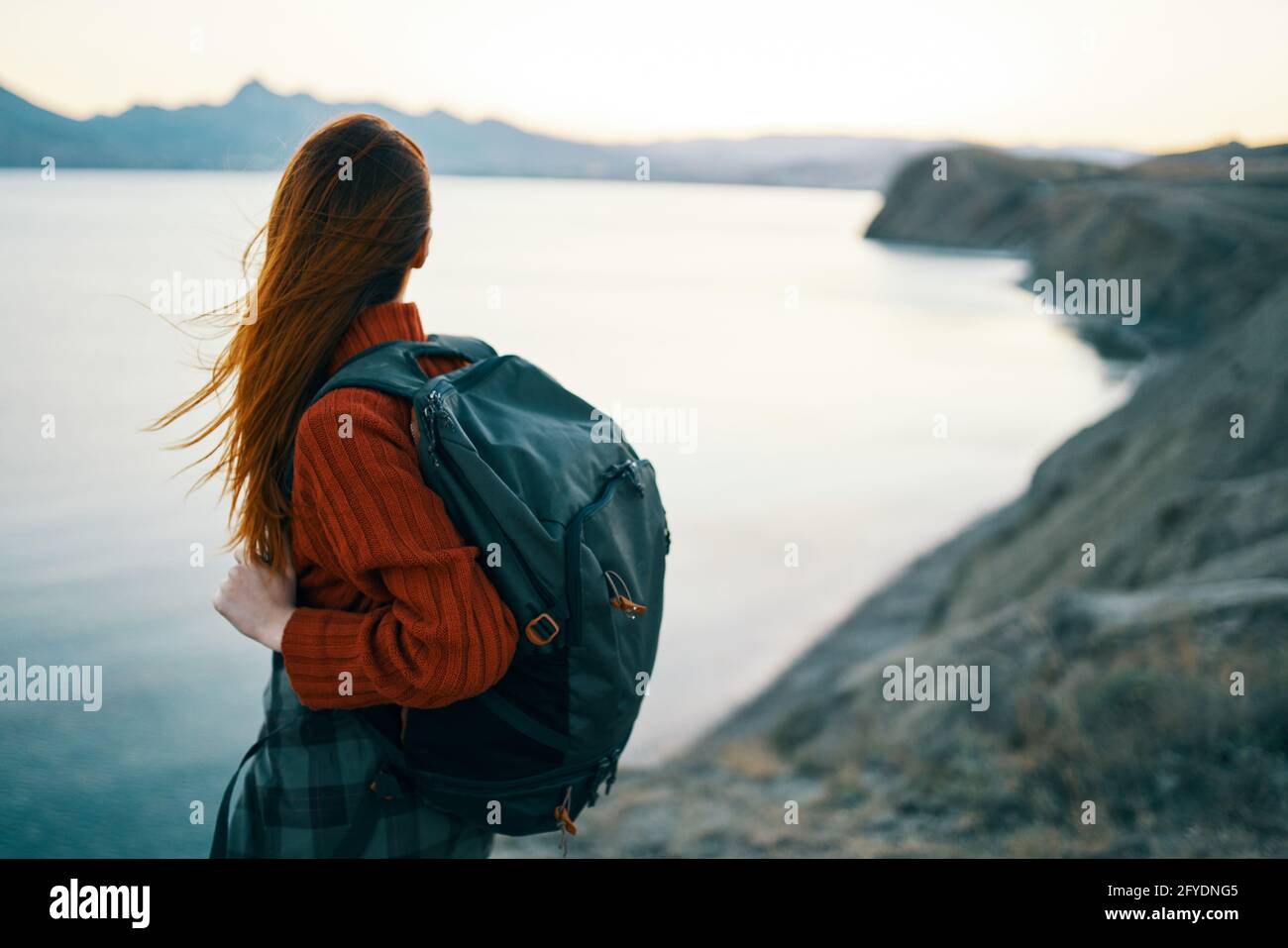 woman in red sweater with backpack and travel tourism sea mountains ...