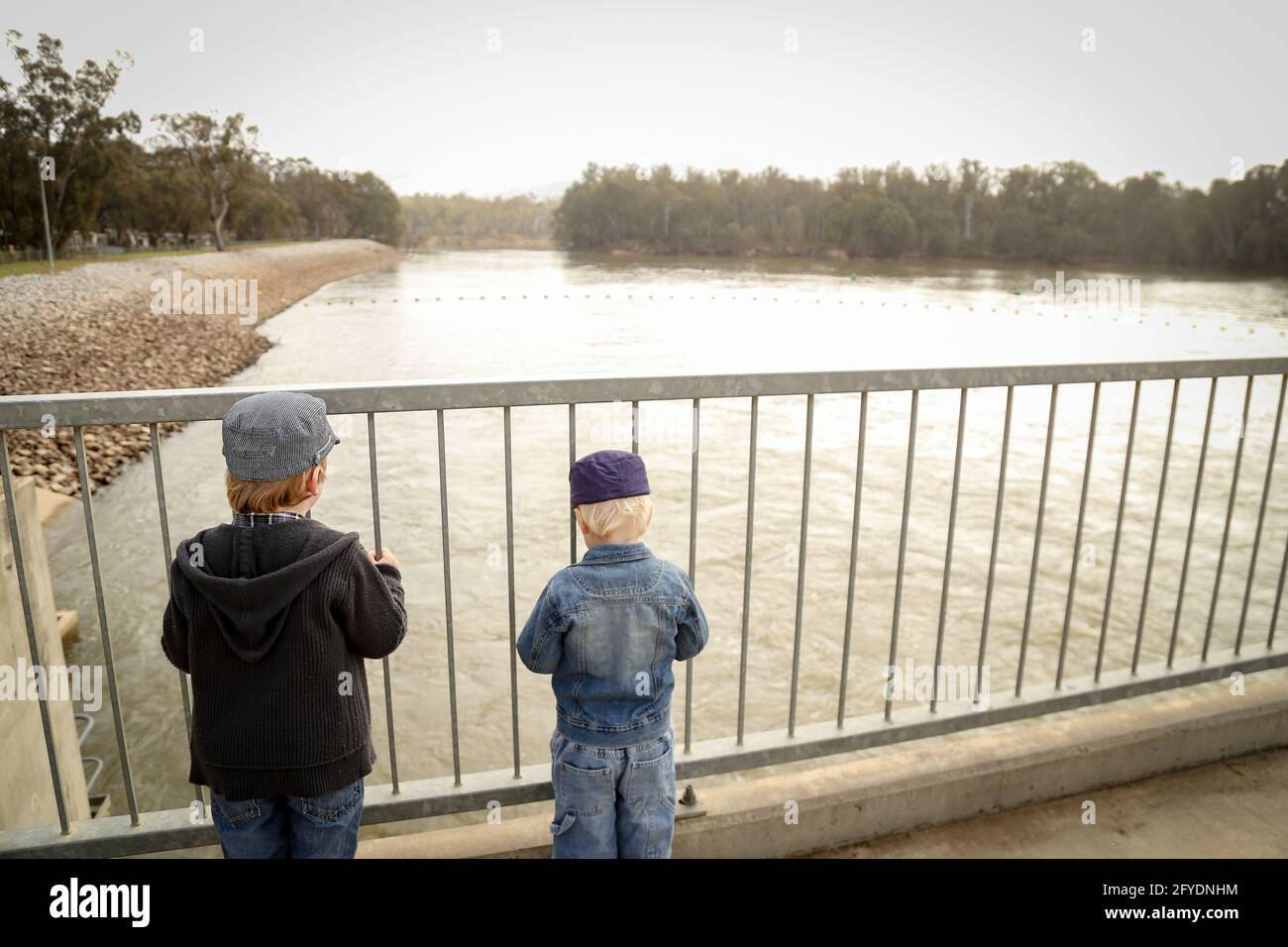 High angle shot of two Caucasian blond boys on a bridge over a lake on ...