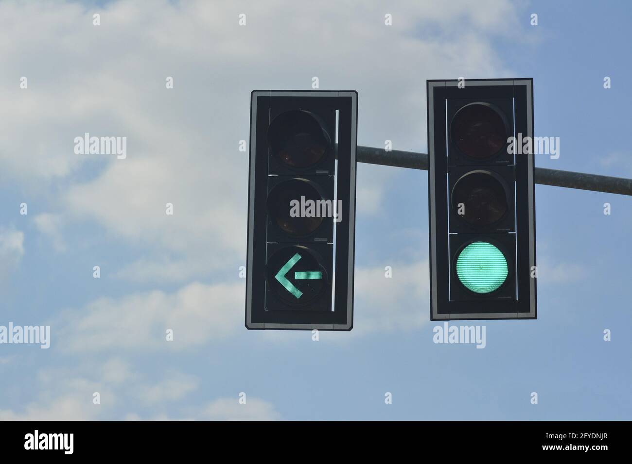 Two traffic lights with a green light and an arrow showing the left ...