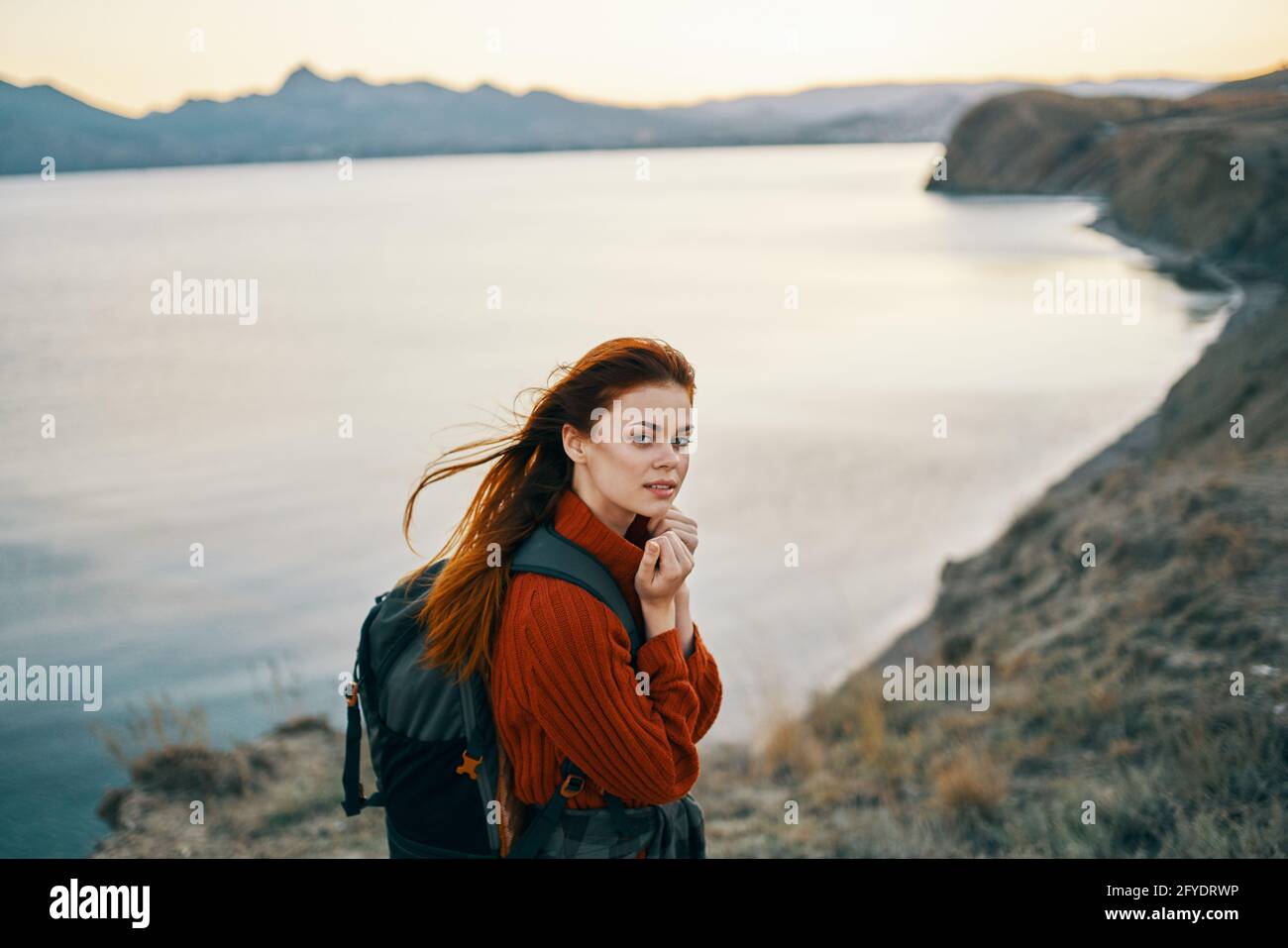 traveler with a backpack in a sweater outdoors in the mountains near ...