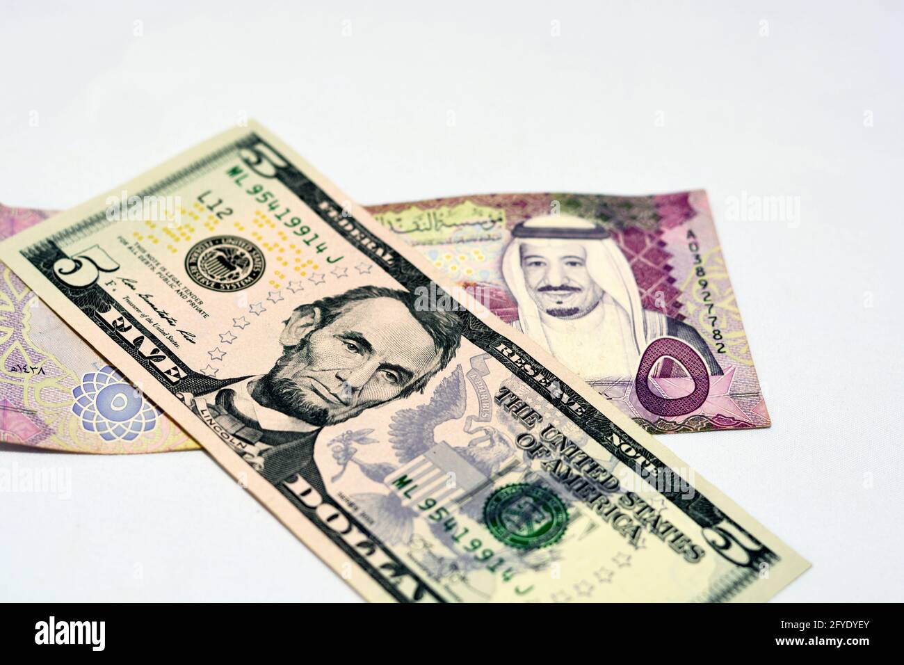 Selective focus of American five dollars bill and Saudi Arabia riyals ...