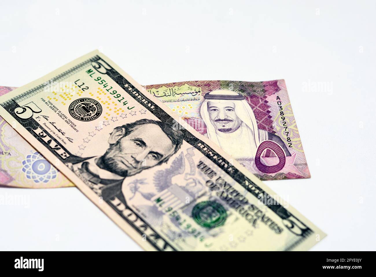 Selective focus of American five dollars bill and Saudi Arabia riyals ...