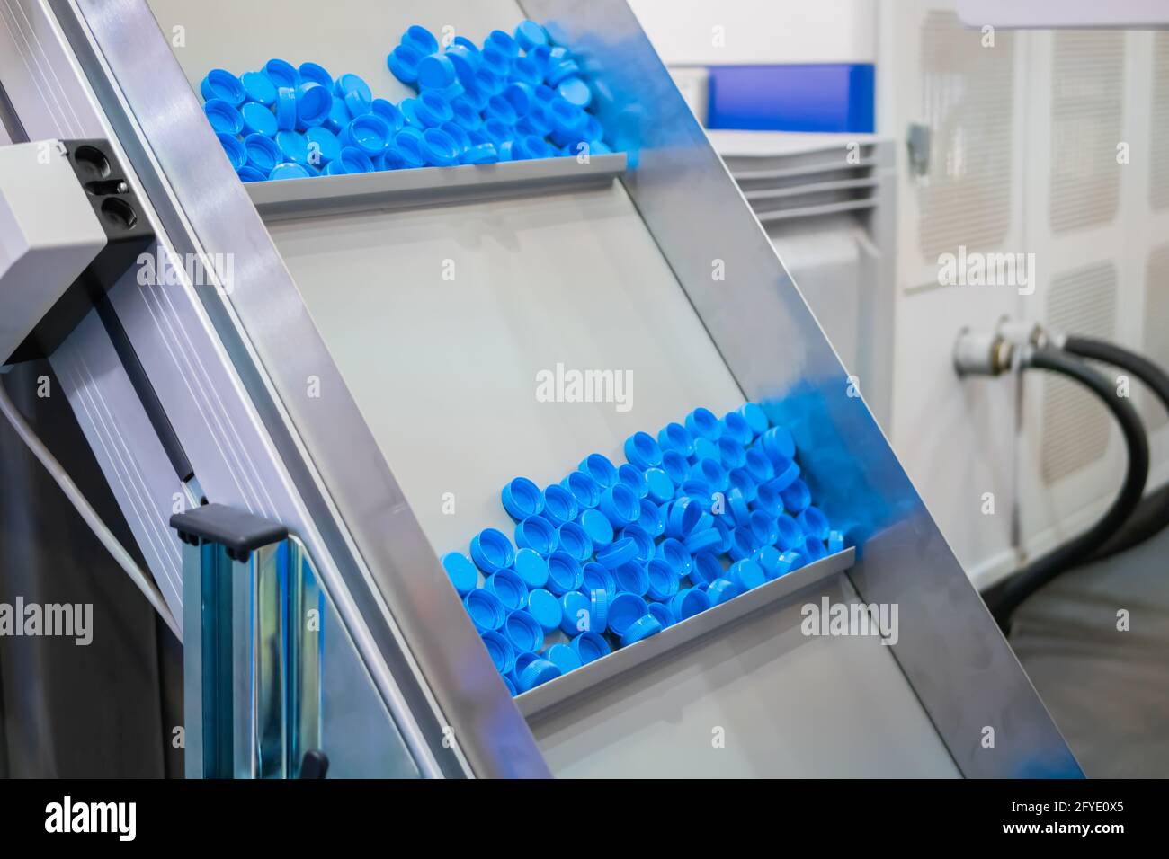 Many blue plastic bottle caps moving on conveyor belt - production line ...