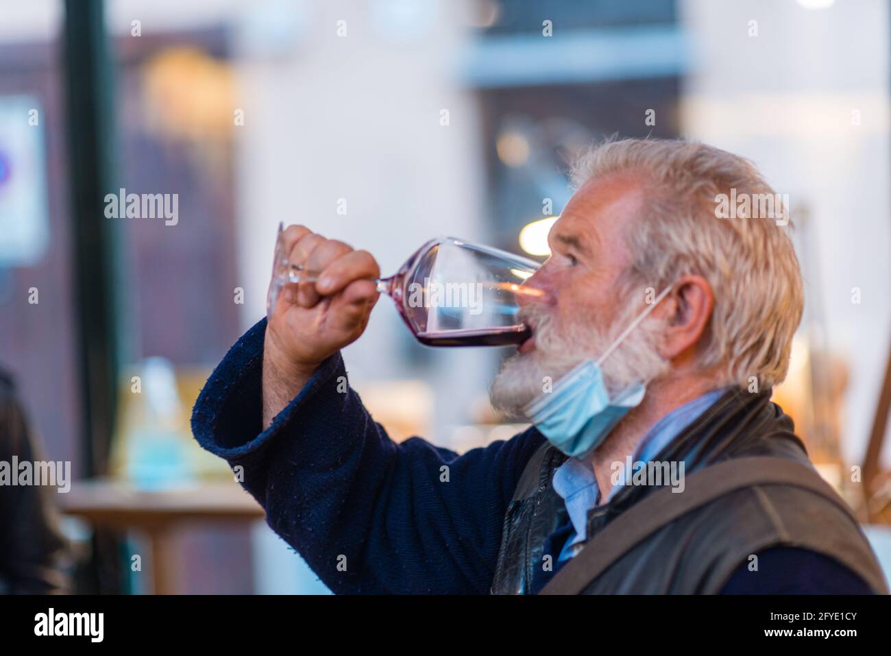 Italian senior male with a face mask pulled down to his chin is ...