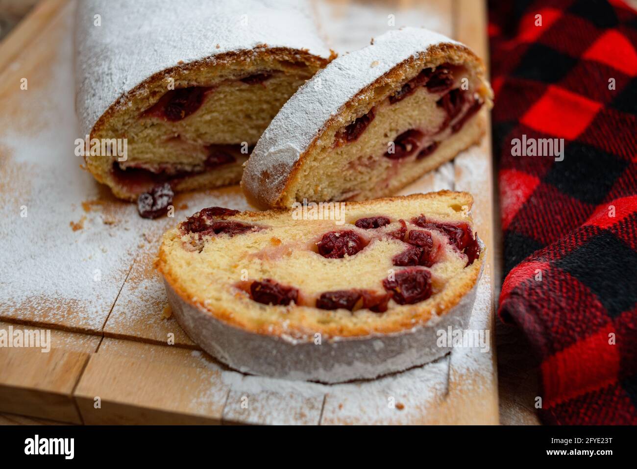 Roll cake with cherry filling covered with sugar powder on a cutting ...