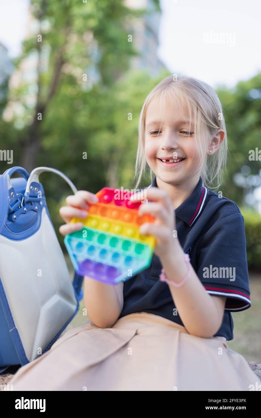 little caucasian girl is playing with new trendy pop it toy ...