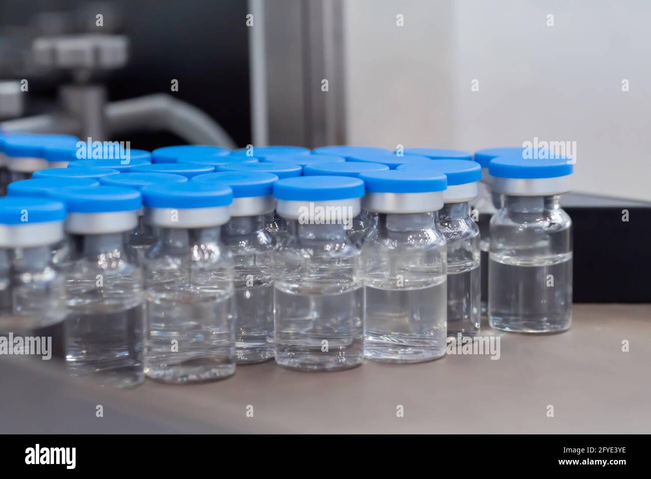 Many medical injection glass vials with blue tops and liquid - close up ...