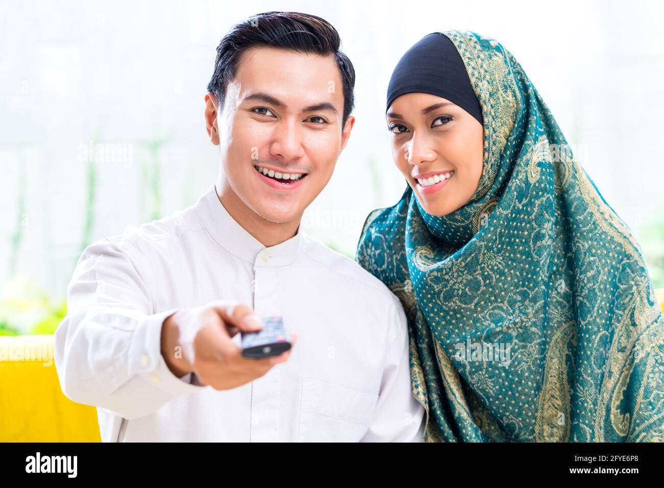 Asian Muslim man and woman watching television in living room Stock ...