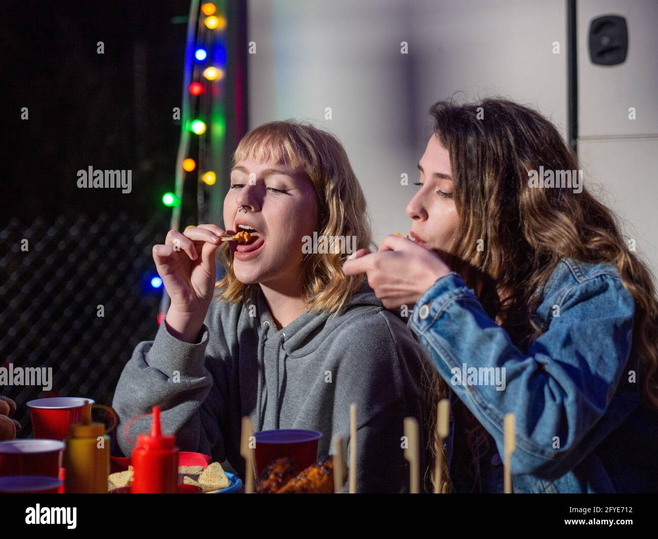 Young female eating cheeseburgers on a party Stock Photo - Alamy