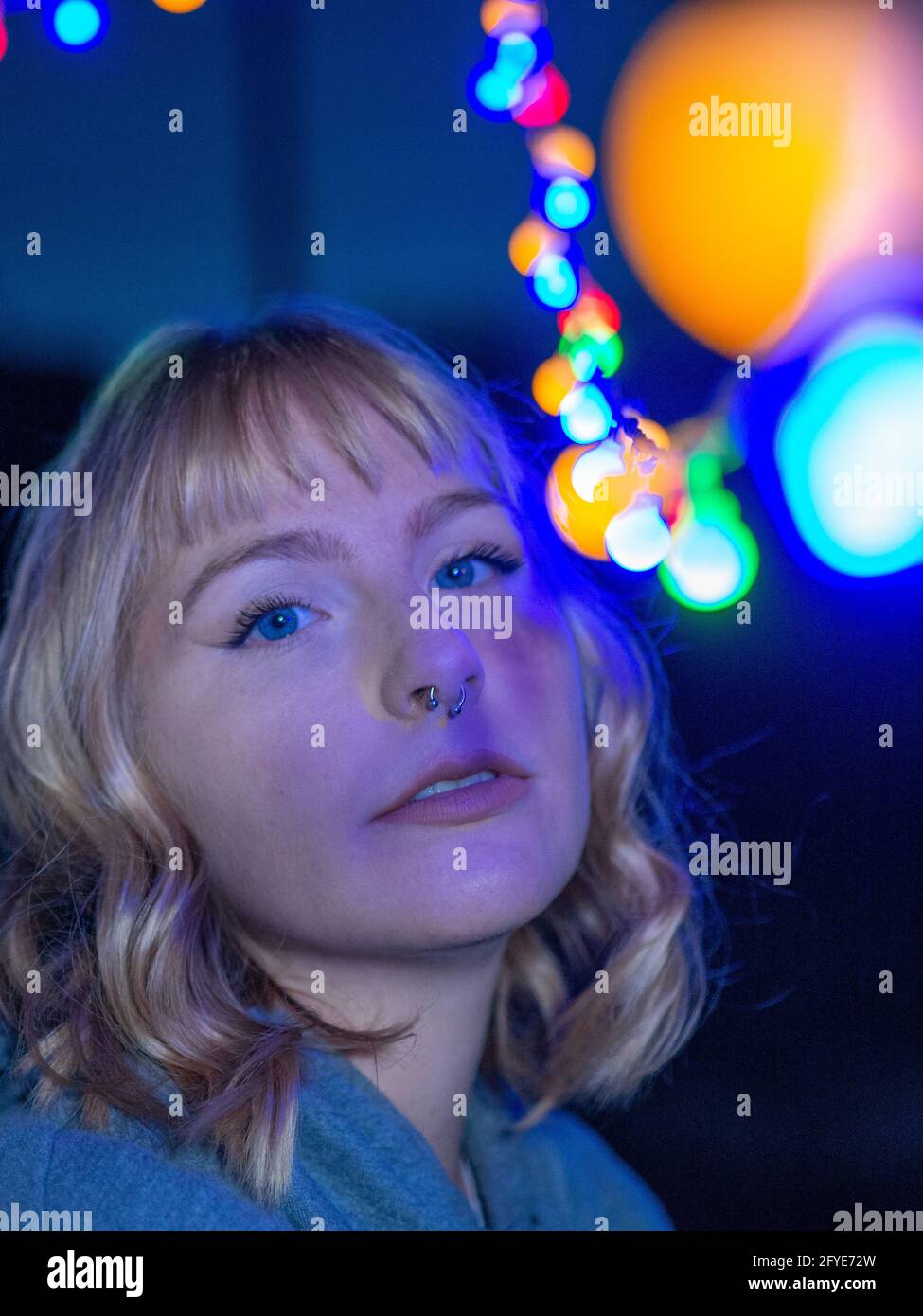 Portrait of a young blonde caucasian female with colorful street lights ...