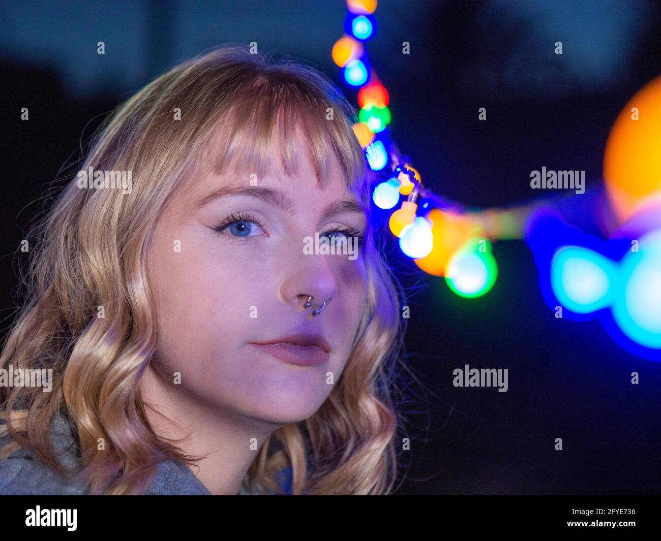 Portrait of a young blonde caucasian female with colorful street lights ...