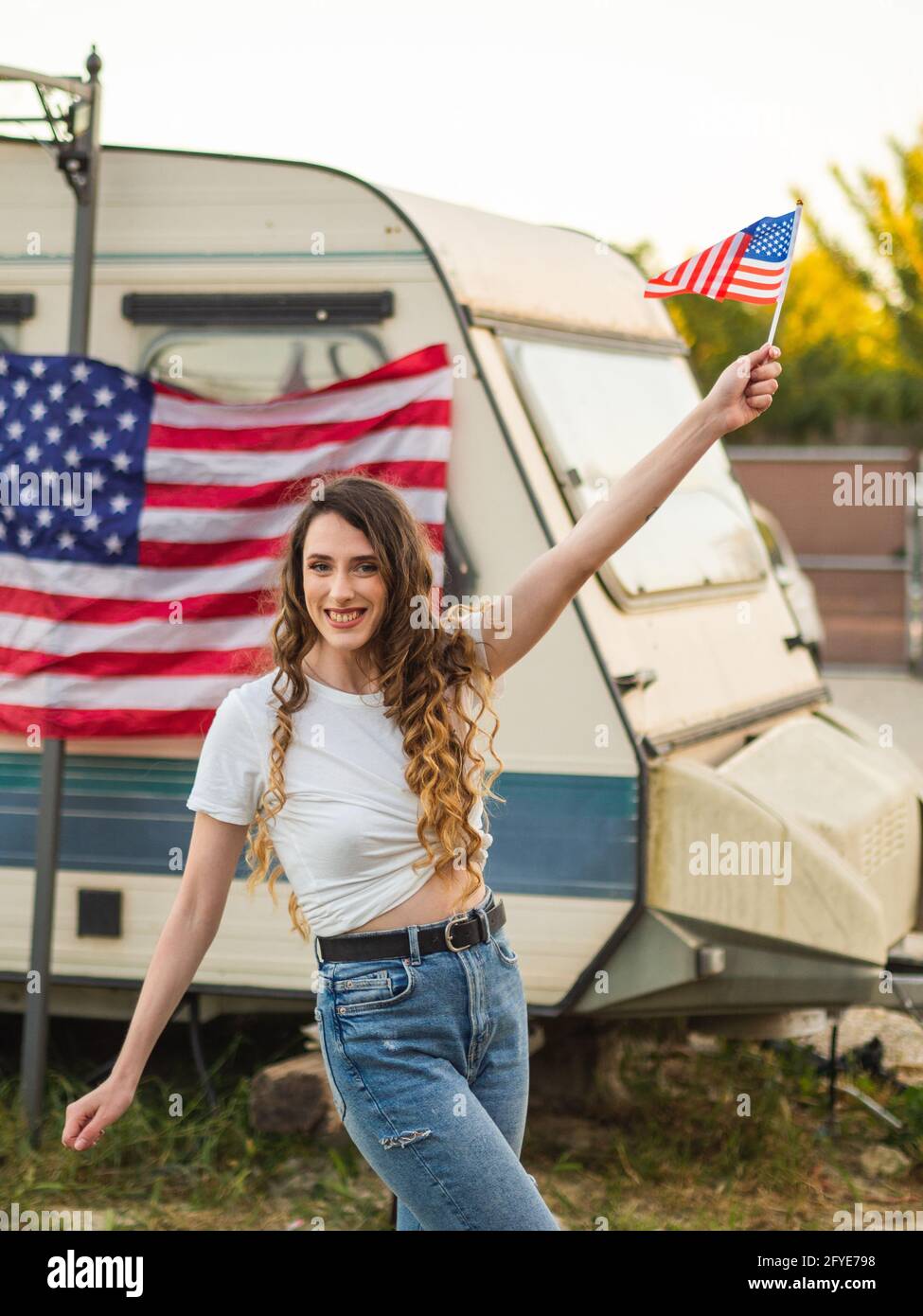 Vertical shot of a blonde Caucasian female posing with the US flag ...