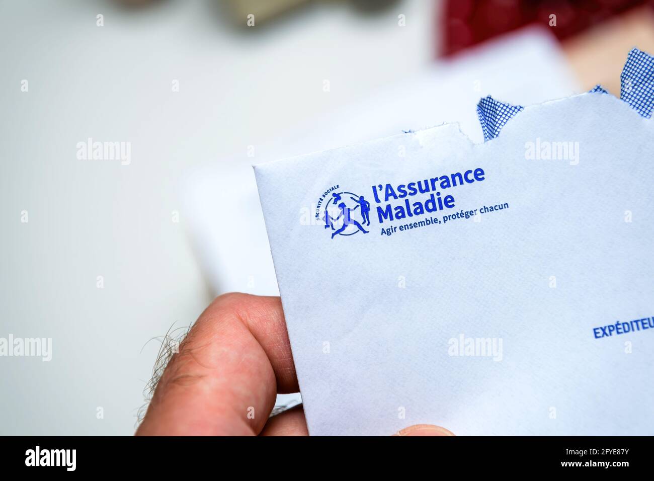 hand holding open envelope from Assurance Maladie translated as French ...