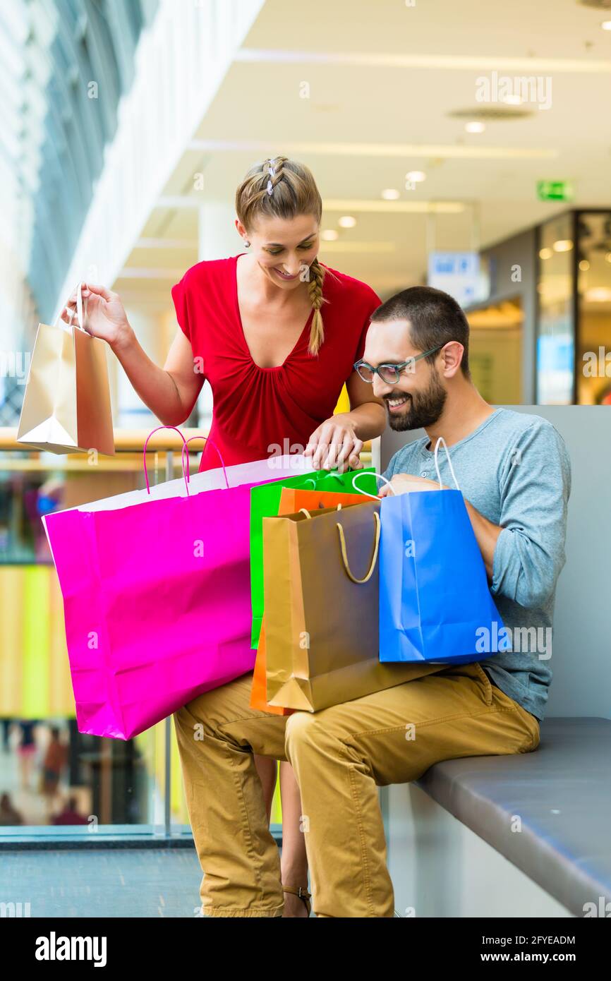 Couple in shopping mall with bags sitting for rest Stock Photo - Alamy