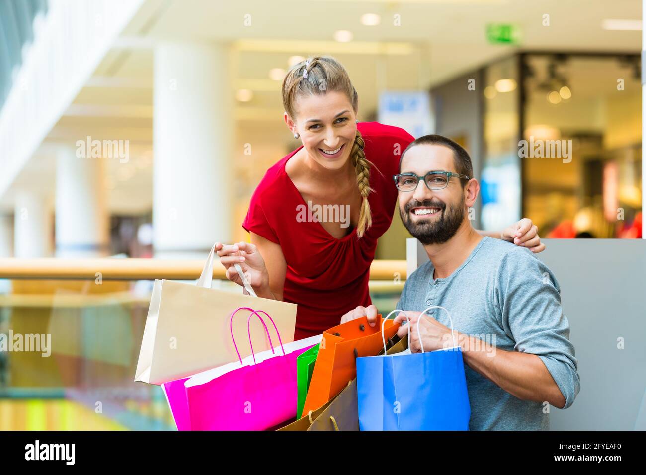 Couple in shopping mall with bags sitting for rest Stock Photo - Alamy
