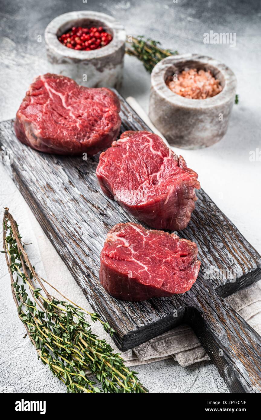 Fillet mignon beef raw steaks on a wooden board with salt and pepper ...