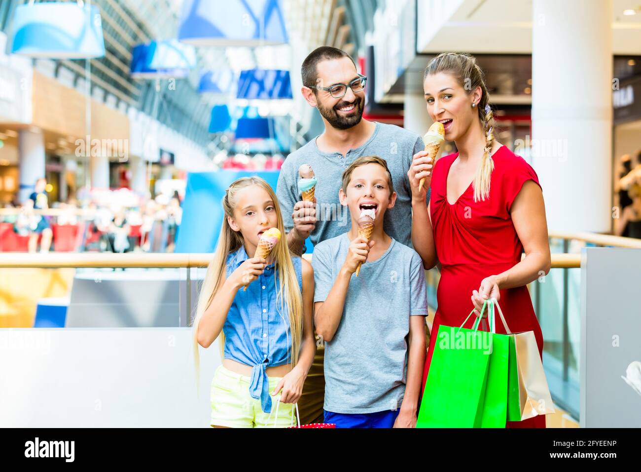 Family eating ice cream in shopping mall with bags Stock Photo - Alamy