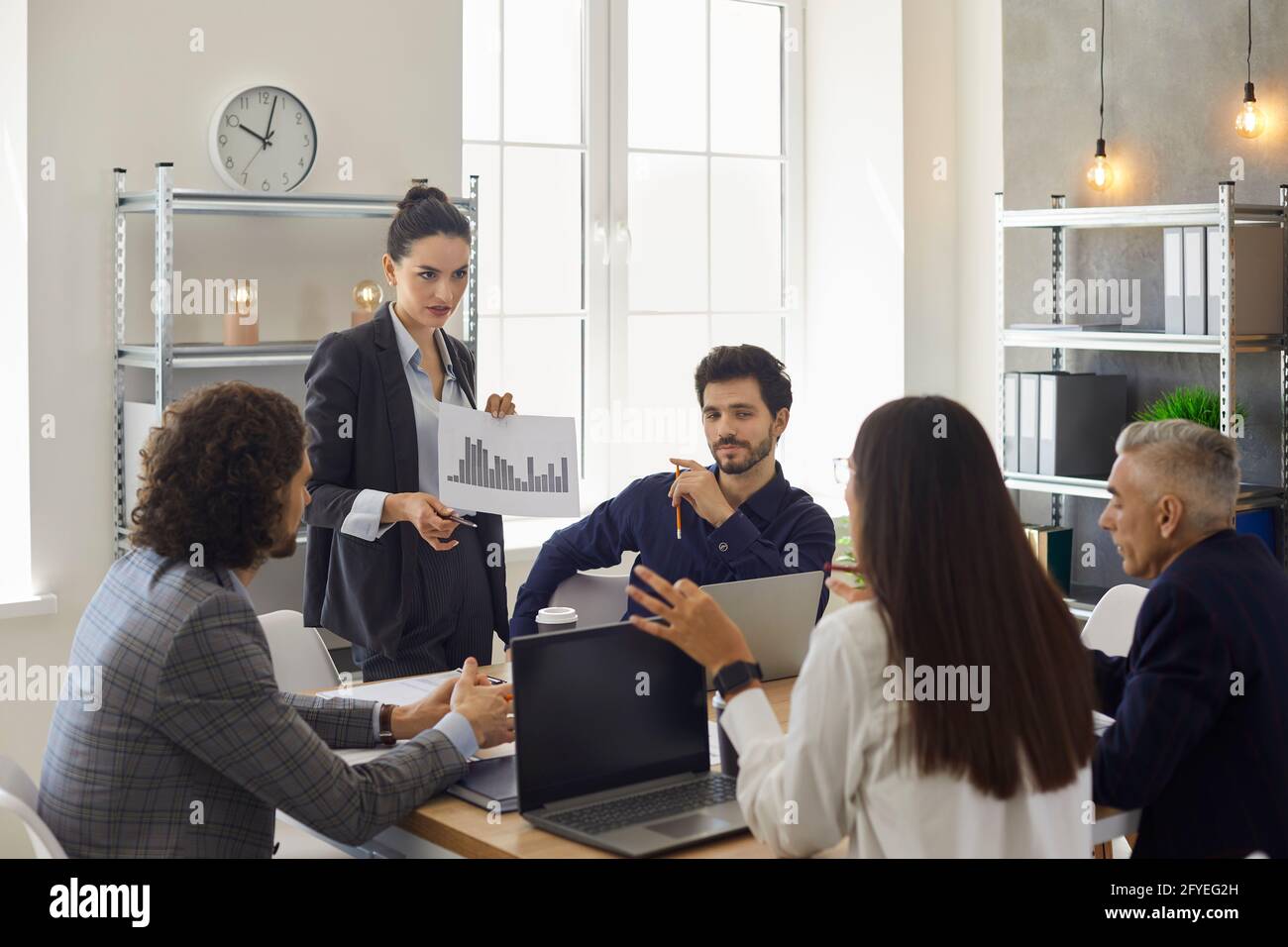 Serious sales team manager listening to her colleague in a corporate ...