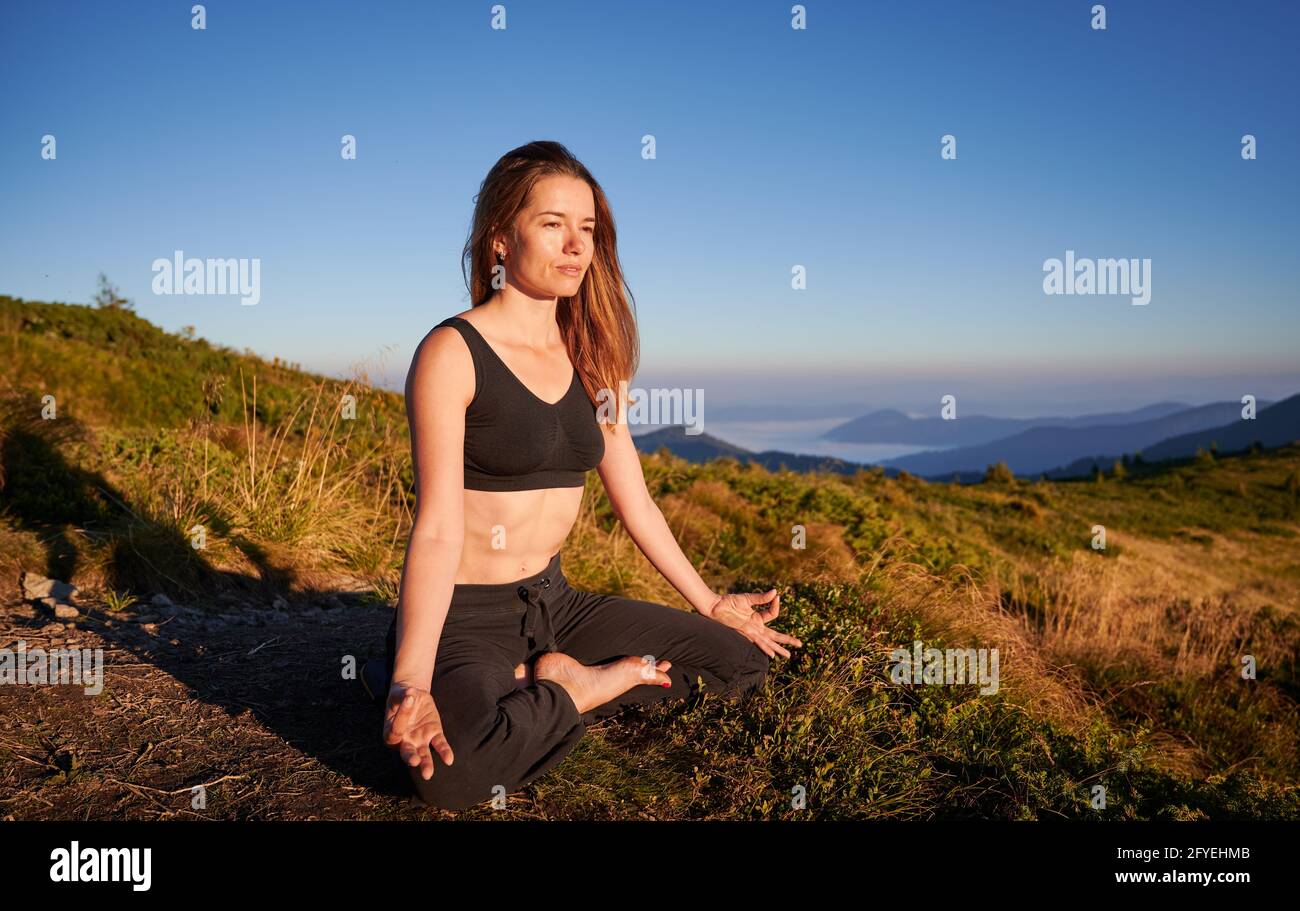 Slim young woman sitting and meditating on fresh air. Concept of yoga ...