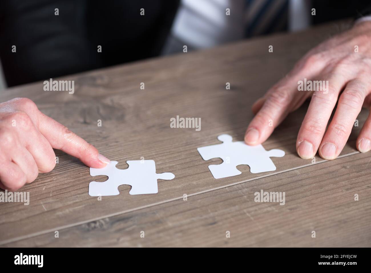 Hands joining two puzzle pieces, teamwork concept Stock Photo - Alamy